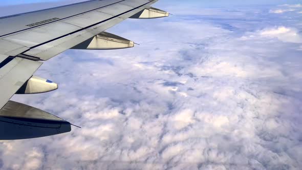 Tilt up of jet Airbus A320 airplane wing flying high in blue sky ...