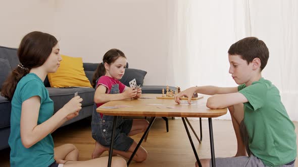 Three kids playing a card game in the living room, shouting and arguing ...