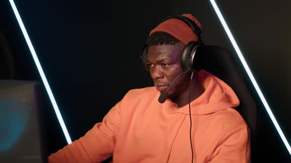 Concentrated Black Gamer in His 20s in an Orange Outfit Carefully ...