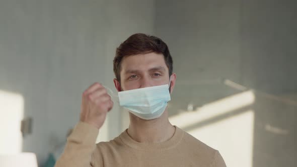 Young smiling guy taking off his mask indoors, Stock Footage | VideoHive