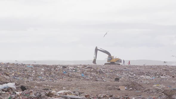 Digger clearing rubbish piled on a landfill full of trash, Stock Footage