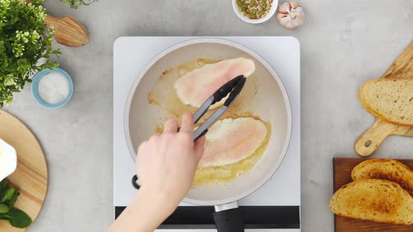 Crop person frying chicken fillet in pan in kitchen, Stock Footage