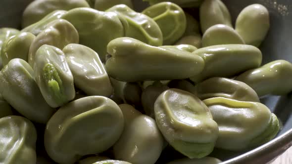 Close up of Fava beans spinning. The beans have been boiled so the skin ...