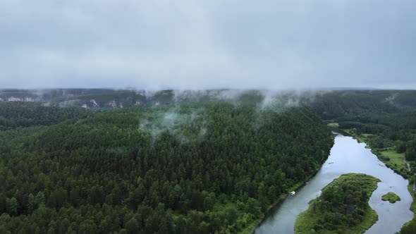 A mystical fog rises over taiga. Hills overgrown with pines on cloudy ...