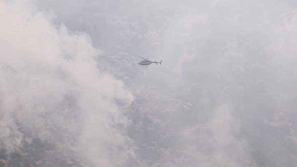 Helicopter flying through smoke of wildfire to survey the area, Stock ...