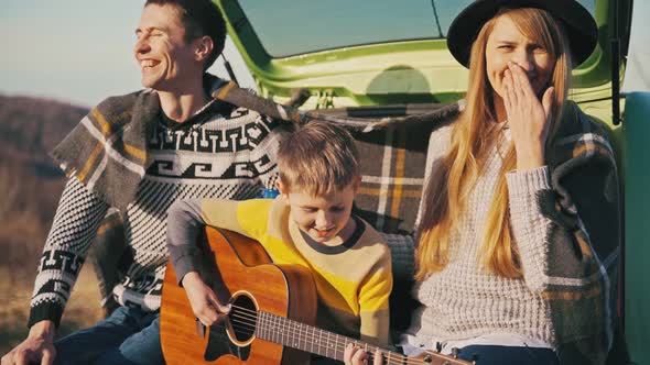 Family Plays Guitar and Sings Songs While Sitting on the Hatchback of ...