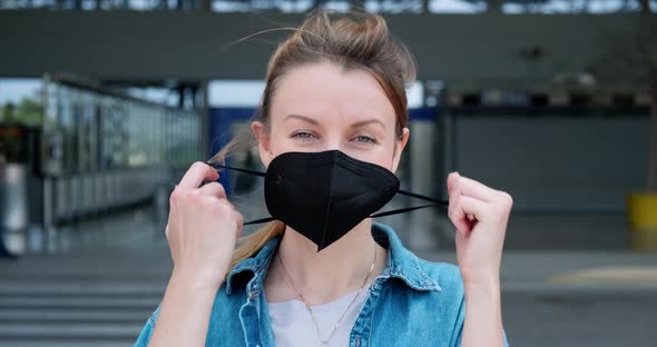Young happy woman taking off face mask at the airport, post pandemic ...