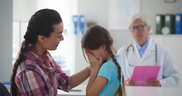 Portrait of Mother Comforting Cute Little Girl Crying at Doctor Office ...