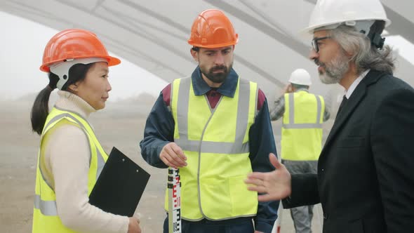Builders Talking at Construction Site While Architect Coming Discussing ...