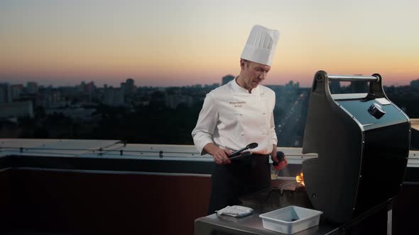 A professional Chef prepares a barbecue on the rooftop of a skyscraper ...