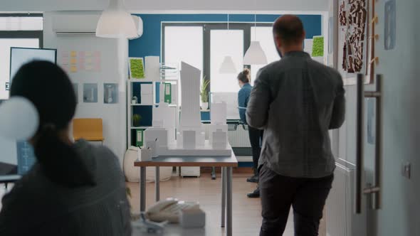 Man Analyzing Blueprints Plan And Building Model On Table To Design Construction Structure