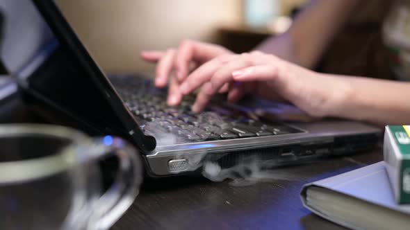 A close-up of an old laptop falling apart with smoke coming out of it ...