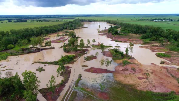 Drone flight over cloudy red clay waters and landscape towards flat ...