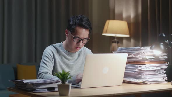 Asian Man Typing Laptop Computer While Working With Documents At Home ...