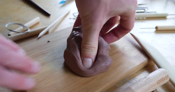 An artist sculpting a project with soft, brown modeling clay by ...