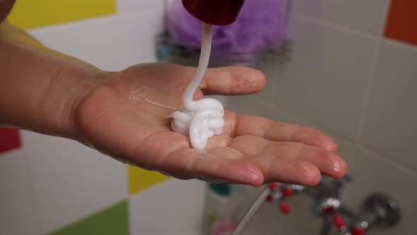 A close-up of a white hair conditioner pouring out of a tube into a ...