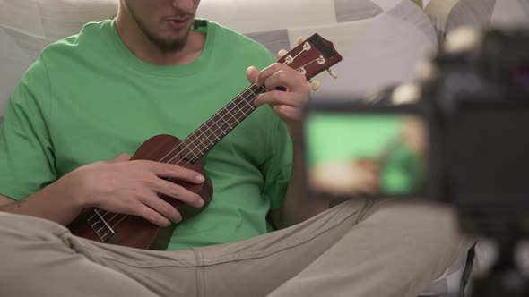 ukulele teacher recording a video tutorial for his students, Stock Footage