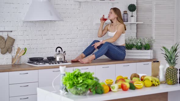 Woman In Modern Combination Of Kitchen. Young woman sitting on table ...