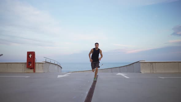 Athlete Runs Fast By Levels of an Empty Parking Garage Front View ...