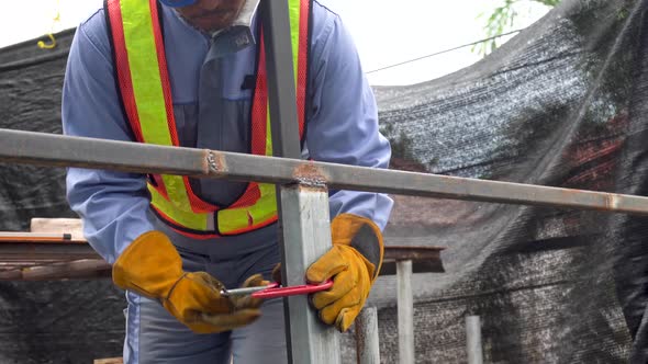 Construction worker attaching a C clamp the arms of a steel bar and ...