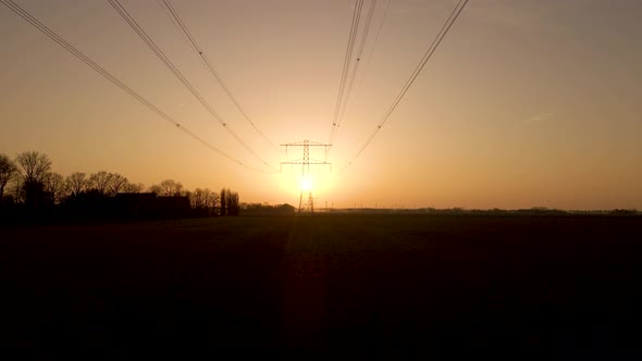 Drone flying under Powerlines in Backlit, High voltage towers as ...
