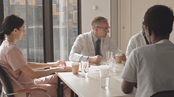 Multiethnic Doctors Sitting around Table during Council, Stock Footage