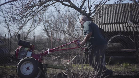 Side View of Mature Caucasian Male Farmer Making Furrows with Furrower ...