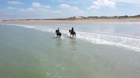 Aerial view of people riding horse along the shoreline in Belgium ...
