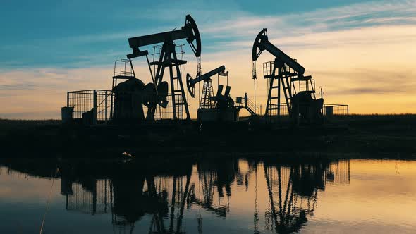 Oil Pumpjacks Working at Oilfield Reflected on Water Surface, Stock Footage