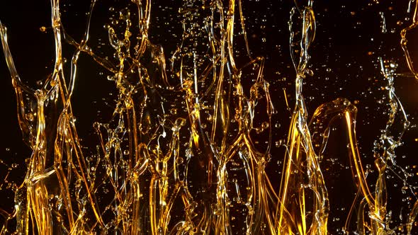 Super Slow Motion Shot of Splashing Golden Oil on Black Background at ...