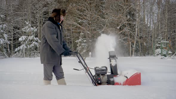 Man Cleans Road From Snow With Snow Plow On Background Of Forest In ...