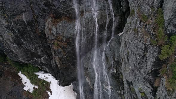 Aerial Of Fresh Winter Snow Melt Trickling Down Big Mountain Rock Cliff ...