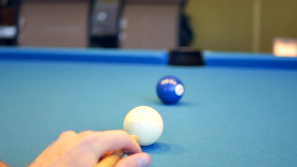 Pool player hitting a ball into the center pocket on a blue felt ...