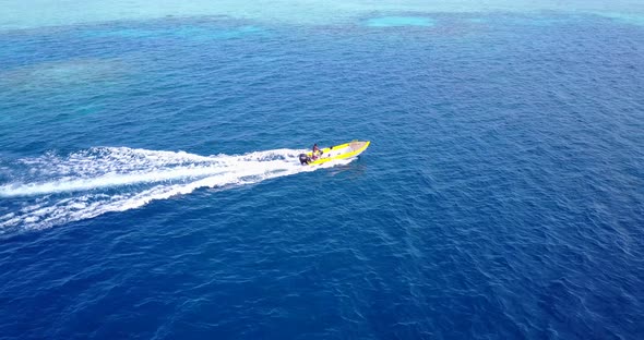 Yellow speed boat tracing across deep blue sea and azure shallow waters ...