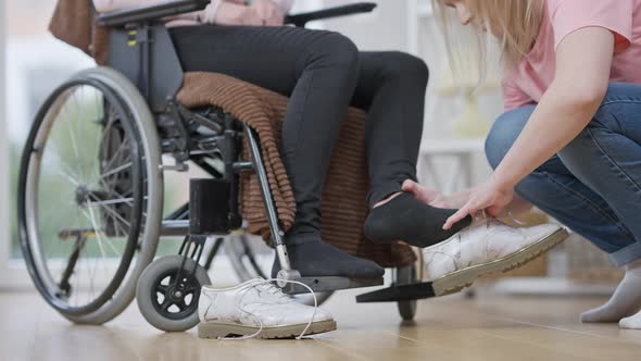 Caring Young Caucasian Woman Putting Shoes on Paralyzed Legs of ...