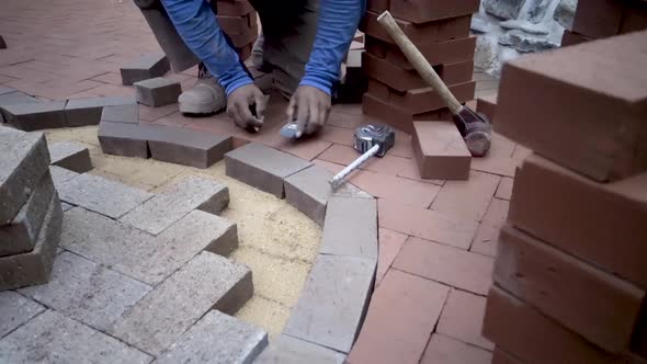 Worker measures and marks a brick for cutting to fit the two tone paver ...