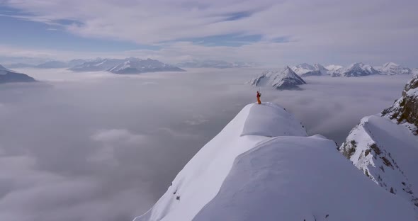 Aerial drone view of a mountain climber skier on the peak summit top of ...