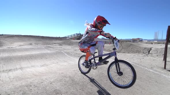 A young woman bmx rider riding bike on a dirt track., Stock Footage