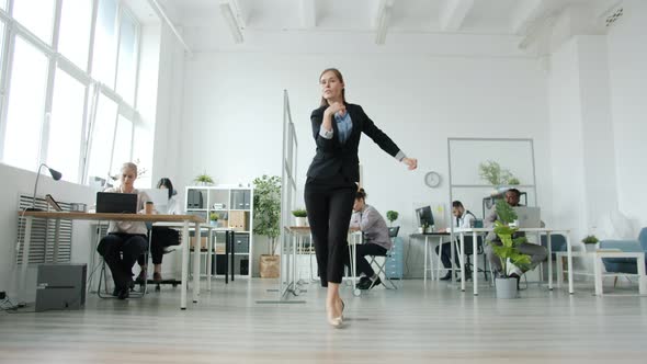 Elegant Young Woman Dancing in Workplace Moving to Music While ...