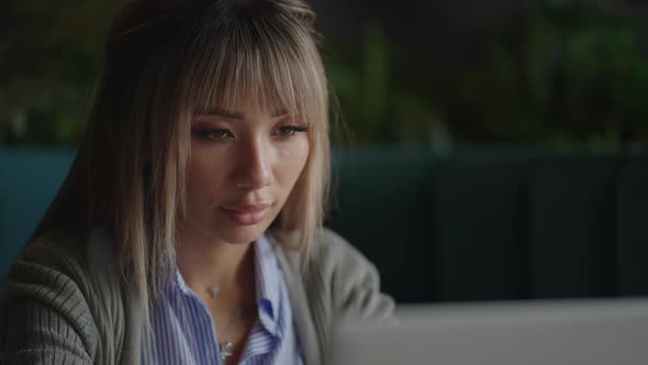 An Asian Woman Sits Brooding and Looks at a Laptop Screen, Stock Footage