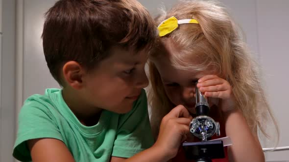 Cute Little Children are Sharing a Microscope with Each Other in White ...