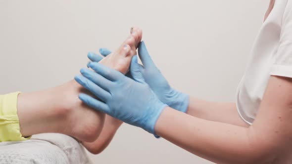Podologist in blue medical gloves smears cream on a female's foot ...