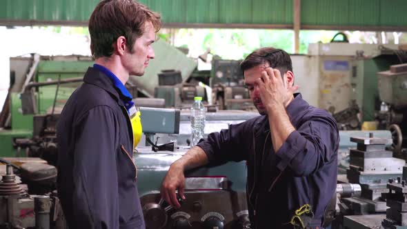 Tired Factory Workers Taking a Break and Talking to Coworker in the ...
