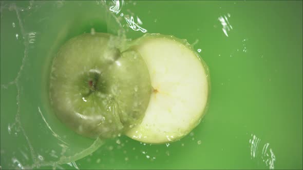 Green Apple Falling on Juice with Splash and Divided in Half, Stock Footage