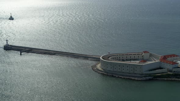 Aerial view of a building by the sea with a long pier and lighthouse ...